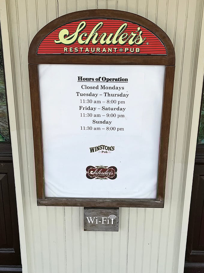 Operating hours posted on the classic Schuler's sign &ndash; a practical detail wrapped in the same vintage charm that defines this Michigan institution.