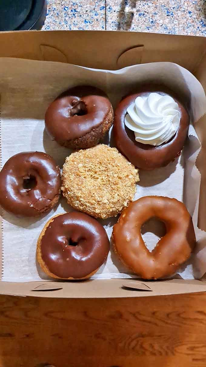 Chocolate-dipped dreams await in this box of golden-fried perfection, where each ring represents decades of donut-making mastery.
