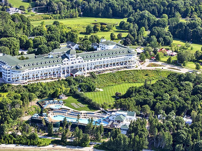 From above, the Grand Hotel's magnificent scale becomes apparent, its pristine white structure and emerald grounds creating a striking contrast against the surrounding forest.