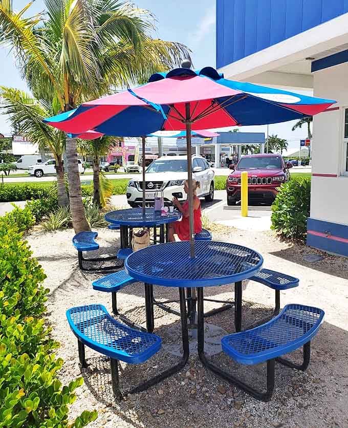 Bright blue tables under colorful umbrellas offer the perfect stage for the ice cream drama about to unfold in the Florida sunshine.