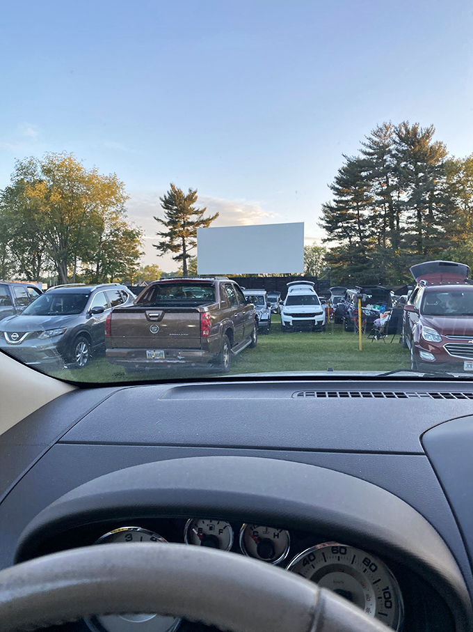 From inside your vehicle, the view captures rows of cars facing the screen – each one containing its own story within the larger narrative.