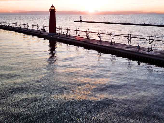 The iconic pier and lighthouse glow at sunset, creating that perfect Michigan moment that makes you understand why people never leave.