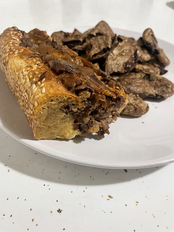 Steak and Spuds: A sesame-seeded roll cradles tender beef alongside those legendary spuds—a perfect partnership on a pristine white plate.