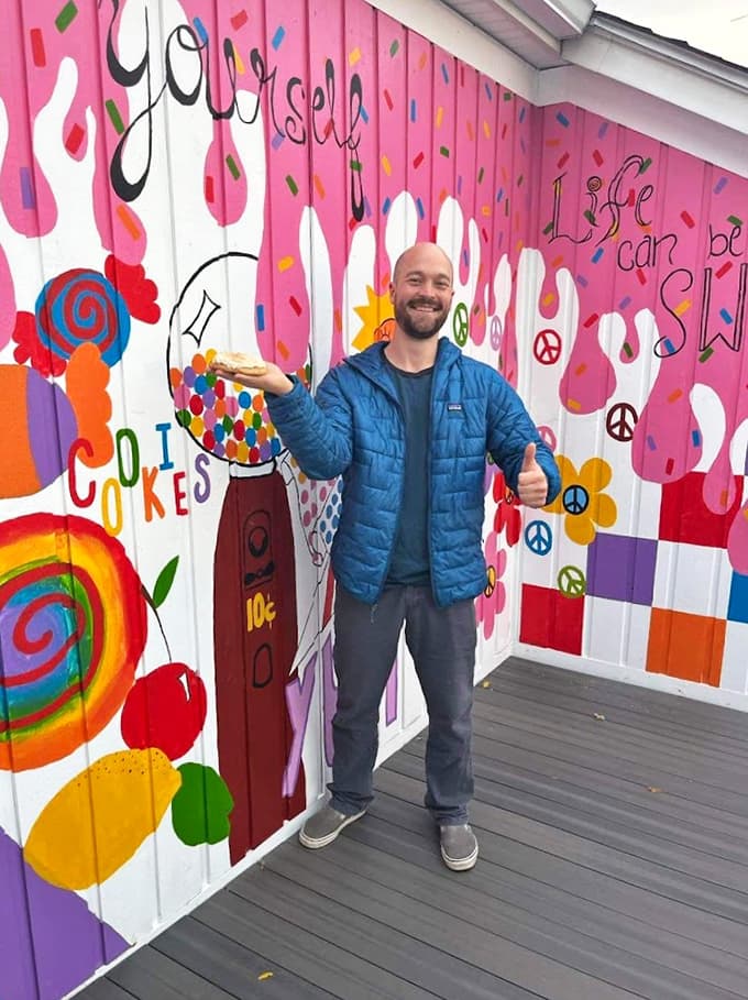 Against a backdrop of rainbow-colored treats, a visitor contemplates the delicious dilemma of which sweet treasure to choose first.