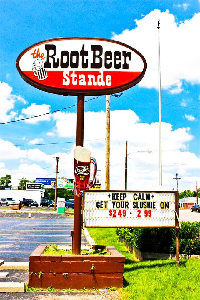 Under blue skies, the Root Beer Stande sign stands tall &ndash; a beacon of Americana offering slushies and memories for generations.