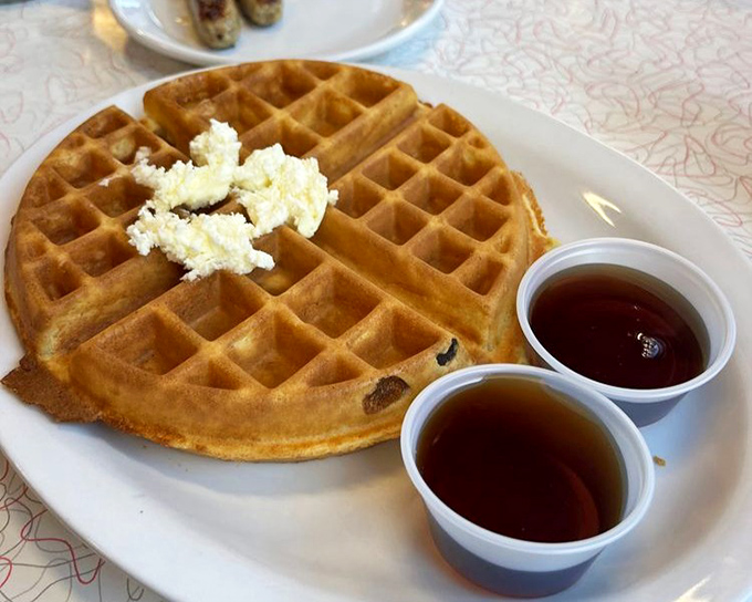 Golden, crispy, and perfectly pocketed &ndash; this waffle stands ready for its syrupy baptism, with a dollop of butter slowly melting.