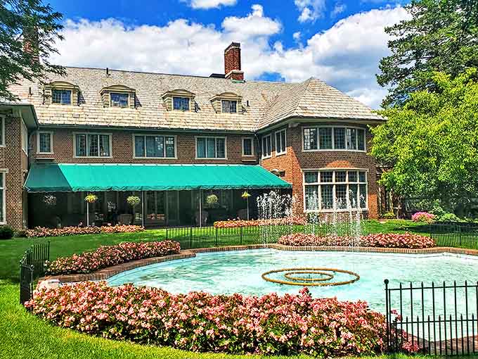The mansion's rear view showcases its impressive fountain, where dancing water creates a mesmerizing focal point amid perfectly manicured grounds.