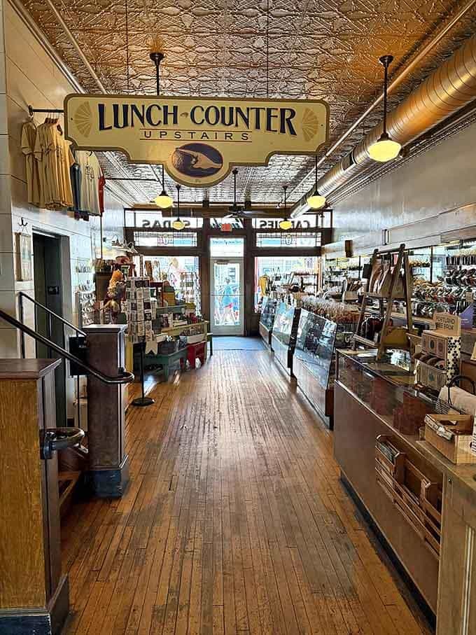The "LUNCH COUNTER UPSTAIRS" sign points the way to culinary treasures, while vintage displays remind visitors they're in a place where history is preserved and celebrated.