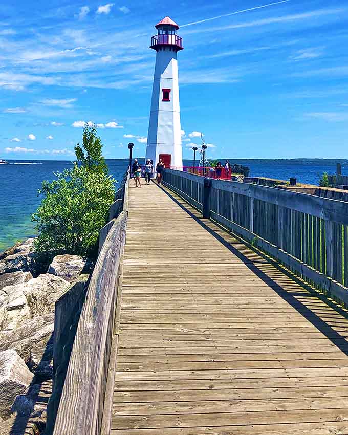 The lighthouse stands as a steadfast guardian at the harbor entrance, guiding vessels safely home long before GPS made navigation a matter of following dots.
