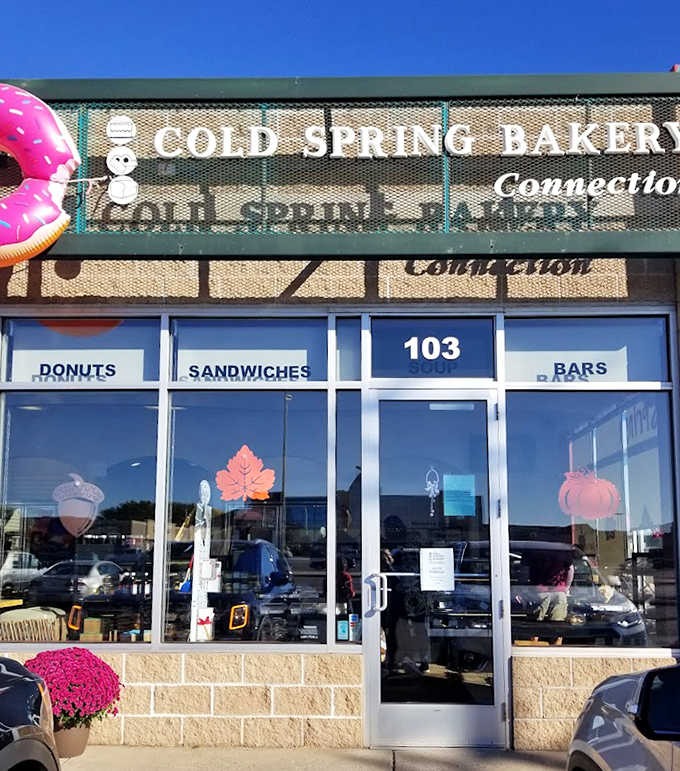 That iconic pink donut sign beckons like a sugary lighthouse, guiding sweet-toothed sailors safely to shore through seas of chain bakeries.