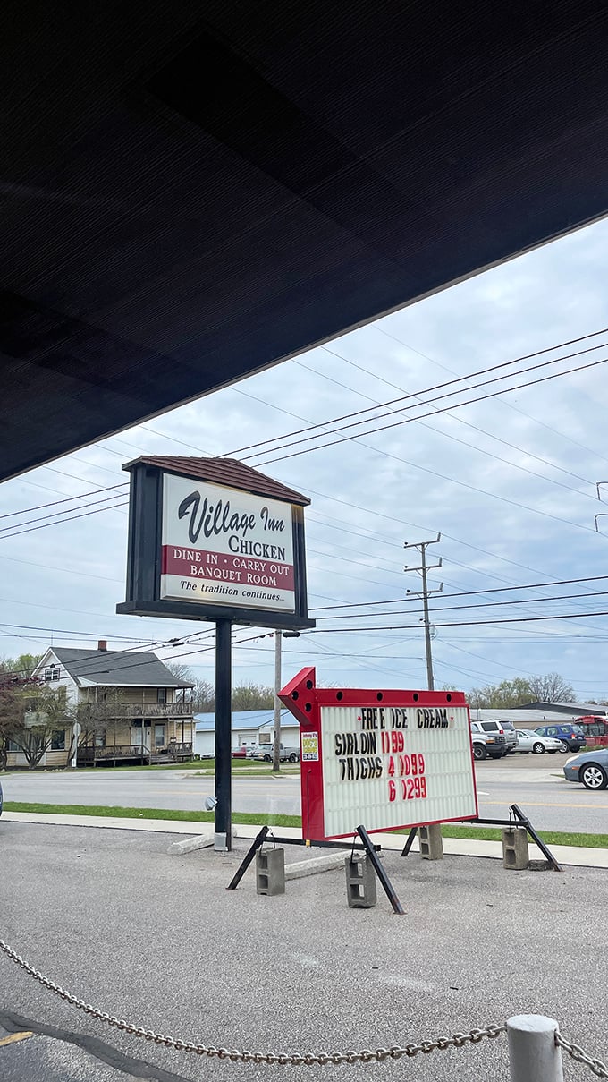 The Village Inn sign stands as a beacon for hungry travelers and locals alike &ndash; a promise of crispy, golden satisfaction waiting just inside.