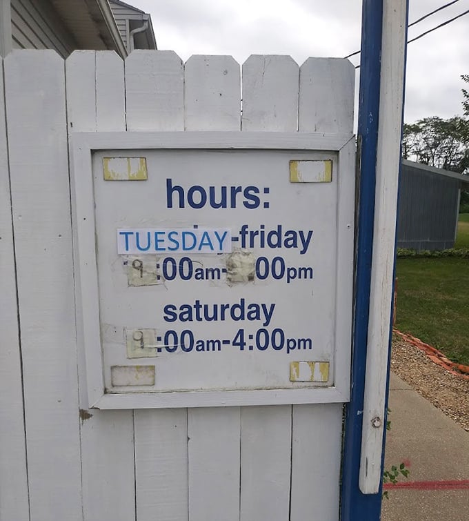 Store hours posted on a weathered white fence &ndash; the gateway to treasure hunting adventures that locals know all too well.