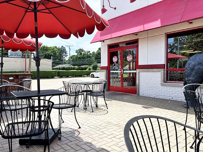 Outdoor Seating: Sun-dappled tables under cheerful red umbrellas create the perfect setting for savoring exceptional food while watching the world go by.