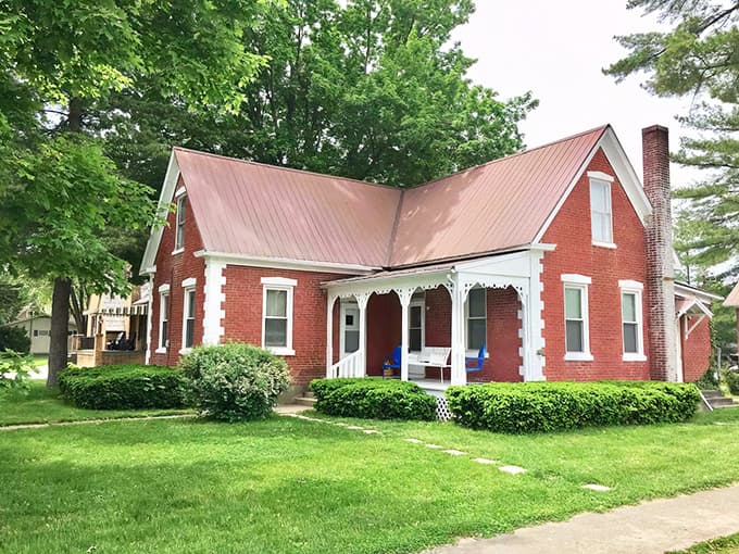 The red brick cottage stands proudly with its copper-toned metal roof and welcoming white porch trim &ndash; a slice of Americana waiting to share its stories.