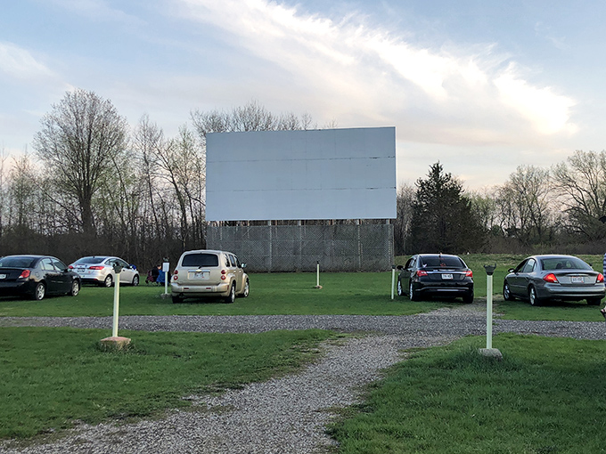 Cars line up at Big Sky Twin Drive-In as the massive white screen awaits the coming darkness. The gravel parking area creates that authentic drive-in experience.