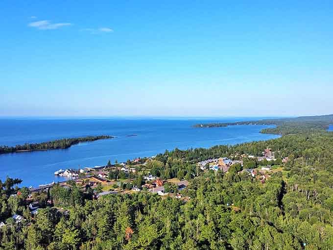 Copper Harbor's stunning coastline stretches into the distance, with dense forests creating a green backdrop against the crystal-clear waters of Lake Superior.