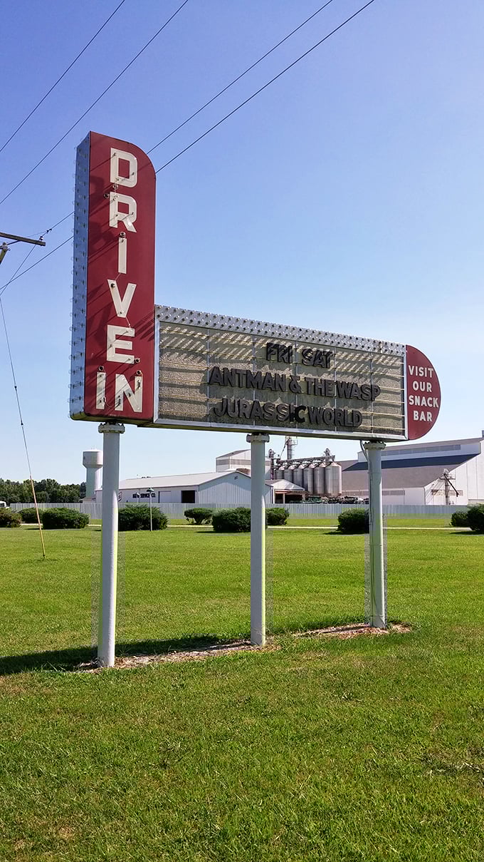 The classic red "DRIVE IN" sign stands tall against blue skies, a colorful landmark promising old-fashioned entertainment that never goes out of style.