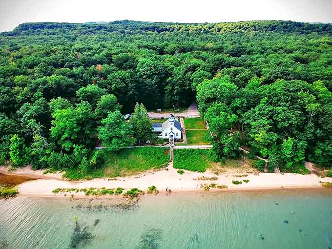 From above, the lighthouse appears like a white chess piece strategically placed between emerald forests and turquoise waters.