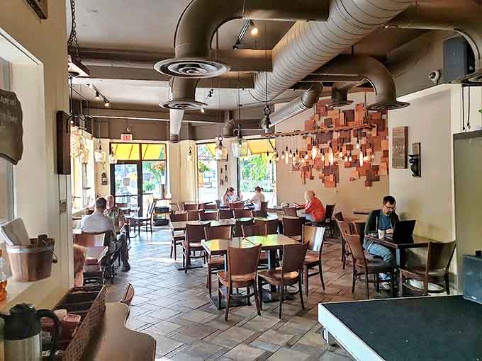 Industrial meets cozy inside Colossal Cafe, where exposed ductwork hovers above warm wooden tables and a unique copper light fixture creates conversation-worthy ambiance.
