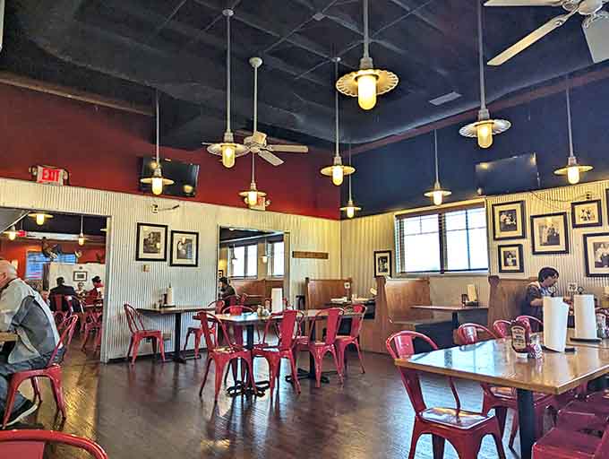 Rustic meets modern in this warm interior where corrugated metal, cherry-red chairs, and vintage lighting create the perfect backdrop for serious eating.