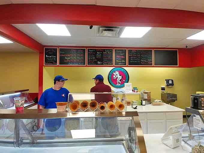 Behind the counter, fresh waffle cones stand at attention while the menu board showcases a tempting array of frozen delights waiting to be scooped.