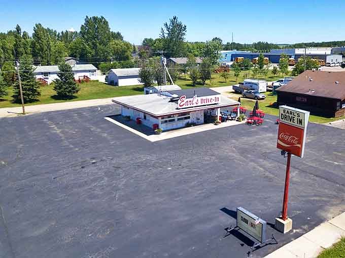 A bird's-eye view reveals Earl's Drive-In in all its nostalgic glory, a white rectangle of culinary history surrounded by Minnesota greenery and loyal customers' vehicles.