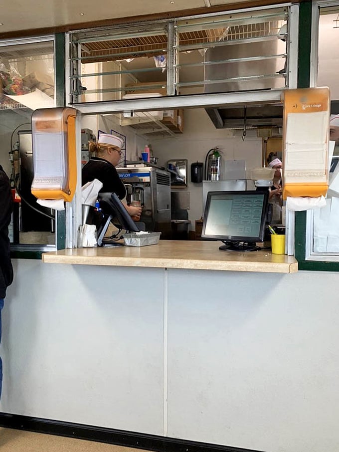 Behind the counter, culinary choreography unfolds as orders are prepared with practiced precision and zero pretension.