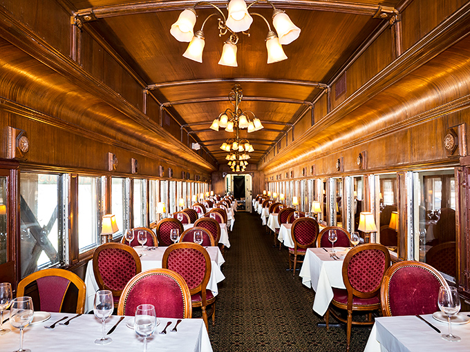 Step inside a bygone era of luxury rail travel where rich wood paneling and plush burgundy chairs create an atmosphere of refined nostalgia.