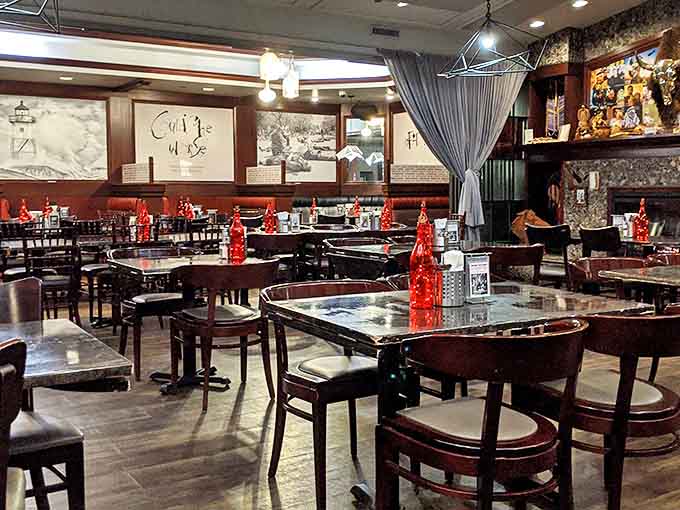 The dining room balances moody sophistication with playful charm, where red accents pop against dark surfaces like culinary exclamation points.