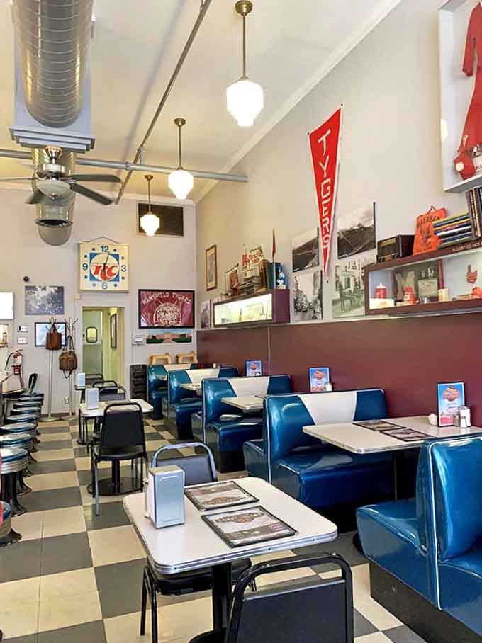 Classic blue booths line the wall beneath vintage pendant lights, creating the perfect backdrop for countless family memories and first-date butterflies.
