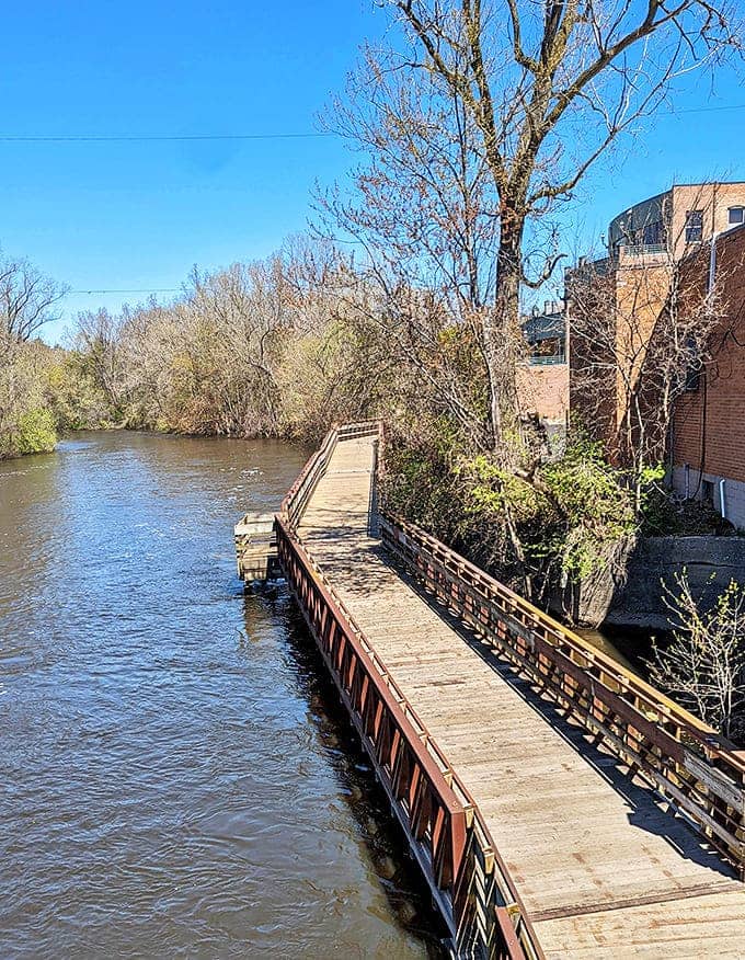 The wooden boardwalk extends over the water like a floating pathway, inviting explorers to venture further into Lansing's riverfront wonderland.