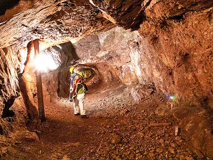 A visitor examines the rugged tunnel walls, where 19th-century miners once chiseled their way through solid rock.