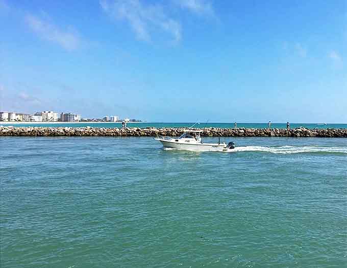 Freedom on the water &ndash; a boat slices through Venice Inlet's turquoise passage, where open sea beckons adventurers.