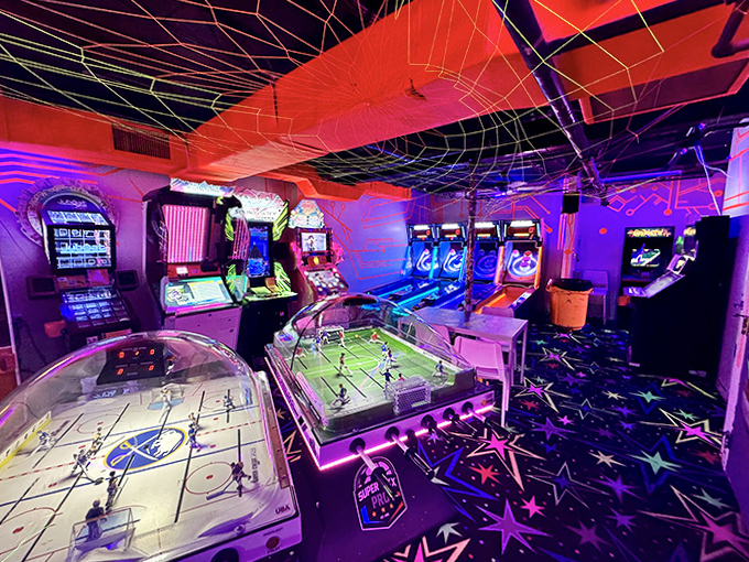Step into a kaleidoscope of gaming nostalgia where neon webs crisscross the ceiling and classic arcade cabinets await your high-score attempt.