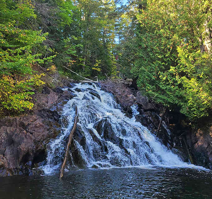 Water tumbles gracefully over weathered stone steps, creating a multi-tiered display that seems choreographed by Mother Nature herself.