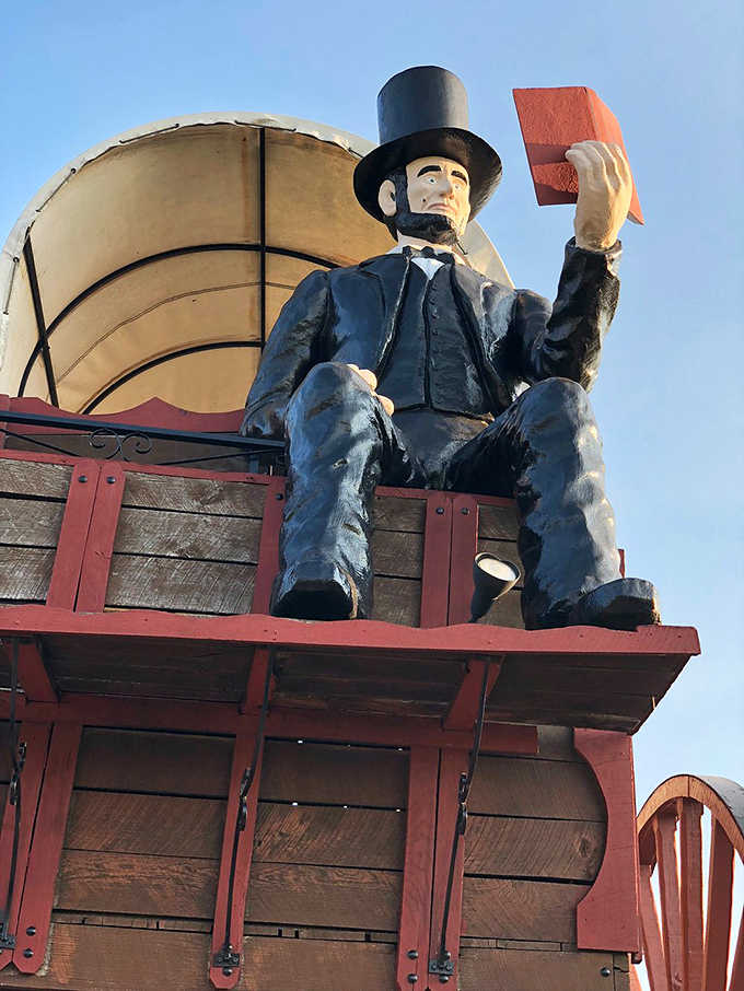 Lincoln studies his law book intently, perhaps contemplating whether "world's largest wagon" was covered in early American legal codes.