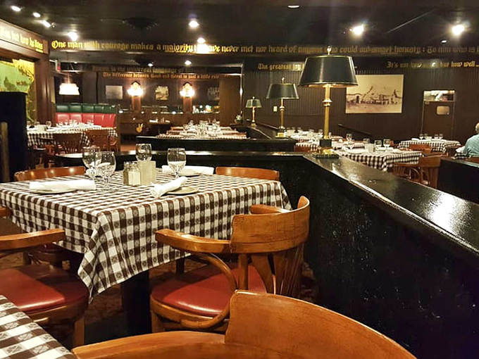 Black and white checkered tablecloths set against dark wood paneling create an atmosphere where time slows down and conversations flow as smoothly as the wine.