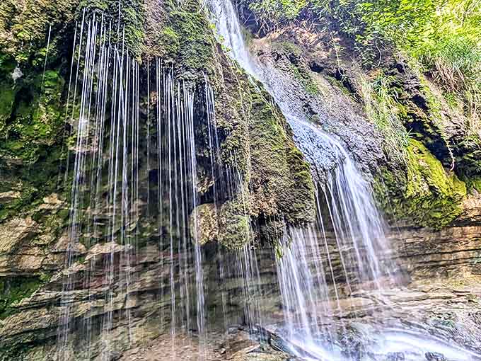 Nature's own waterworks display: Shadow Falls cascades down ancient limestone, creating a mesmerizing curtain of water that dances in dappled sunlight.