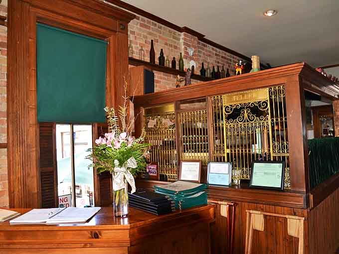 Original teller stations remain intact, now serving as charming host stands where reservations are managed instead of financial transactions.