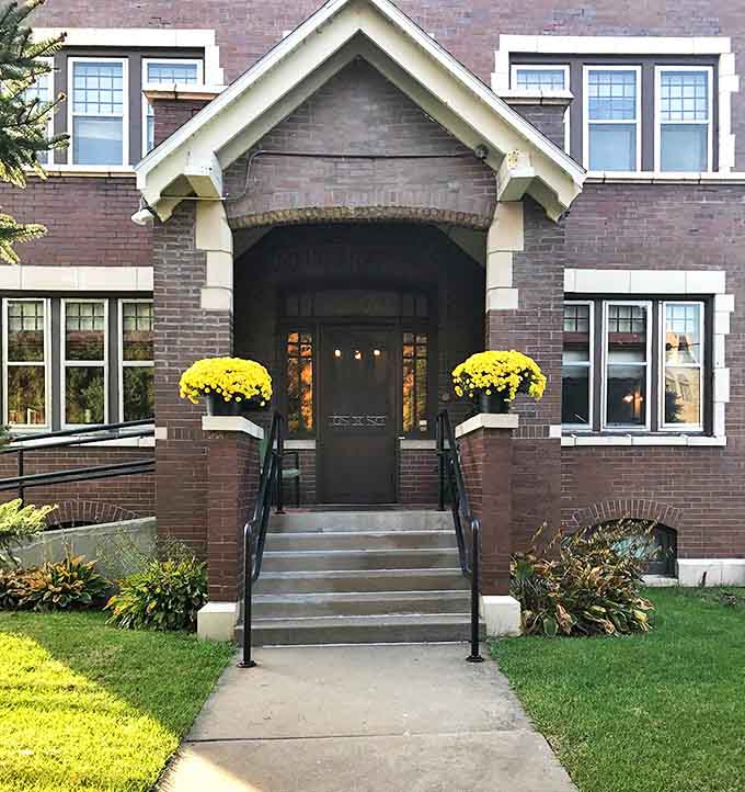 Those welcoming steps and cheerful flowers create quite the contrast with the building's serious architectural bones and barred windows above.