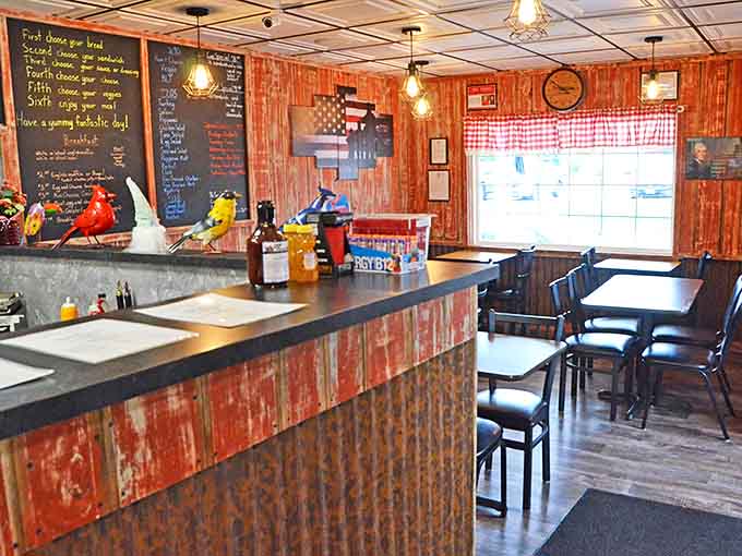 Rustic charm meets culinary precision at the counter, where colorful bird figurines add whimsy to the serious business of sandwich crafting.