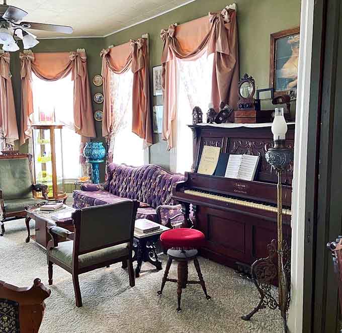 Vintage charm meets cozy comfort in this sitting area where rich green wallpaper and period furnishings create an authentic Victorian atmosphere.