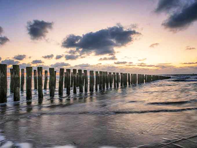 Lake Michigan's shoreline near Zeeland offers breathtaking sunsets that transform wooden breakwaters into silhouettes against the painted sky.