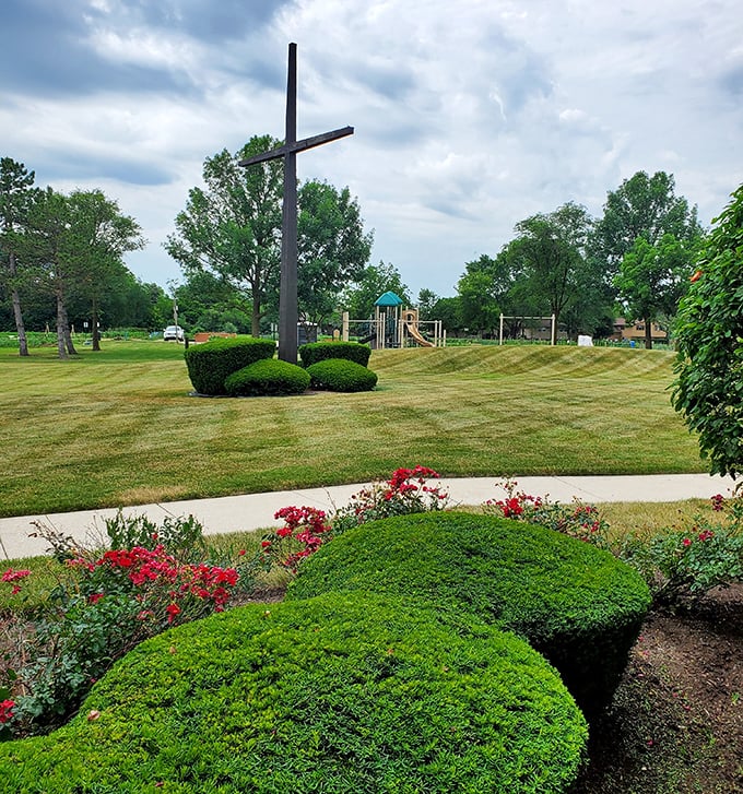 A serene cross rises above meticulously maintained gardens, offering a peaceful spot for reflection amid the bustle of suburban life.