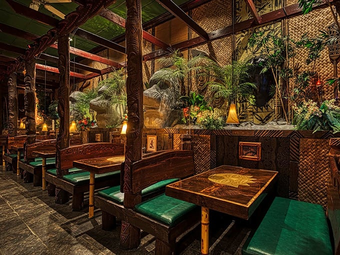 Carved wooden posts and lush greenery transform this dining room into a Polynesian paradise. The bamboo-lined ceiling completes the tropical illusion.