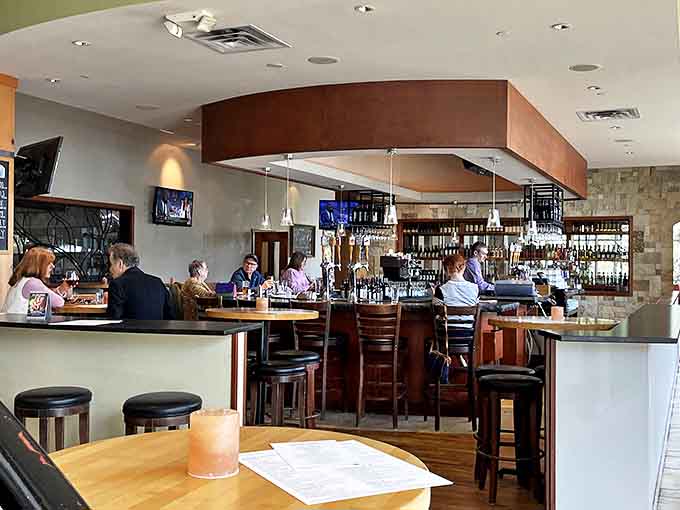 The elegant bar area serves as the heart of Pinstripes, where craft cocktails flow and conversations buzz between frames.
