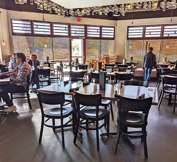 Mason jars dangle from the ceiling, casting a warm glow over wooden tables where comfort food dreams come true.