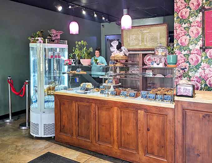 Behind the counter, pastry paradise awaits. The floral wallpaper and vintage touches create an atmosphere that's both elegant and welcoming.