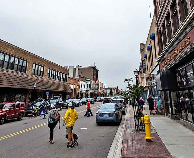 Downtown Marquette buzzes with activity as locals and visitors stroll past historic buildings and colorful storefronts on a typical Michigan afternoon.