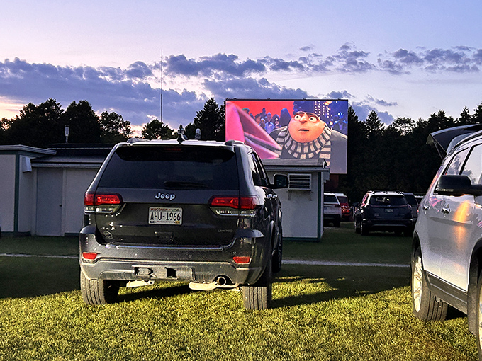Movie magic comes alive at Skyway Drive-In as an animated character fills the screen against the twilight sky. Cars gather in anticipation of nightfall.